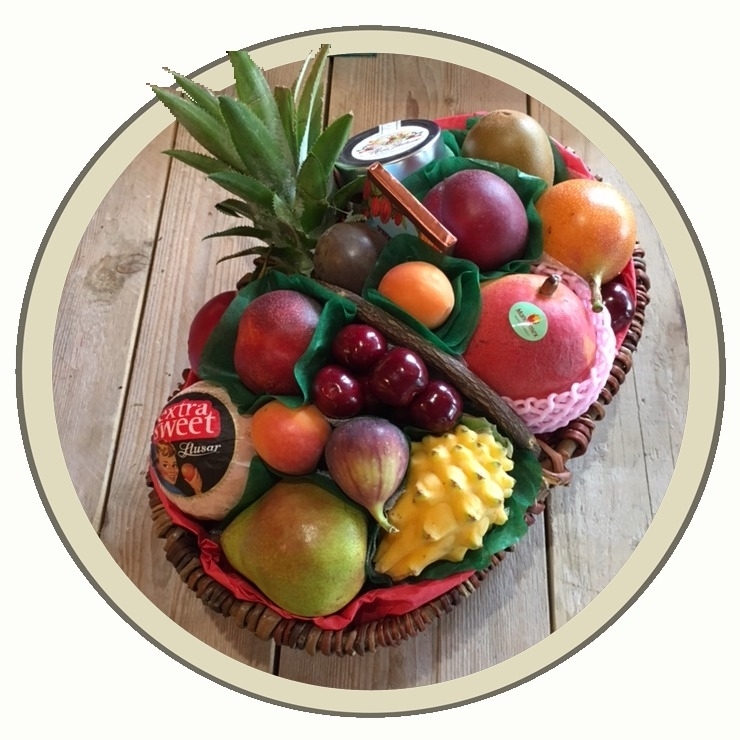 Fruitmand met fruit, wijn, chocolade en bonbons.